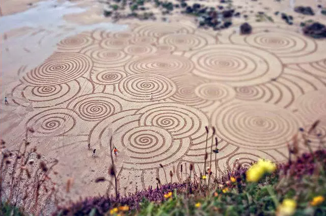 Artisti che disegnano sulla sabbia